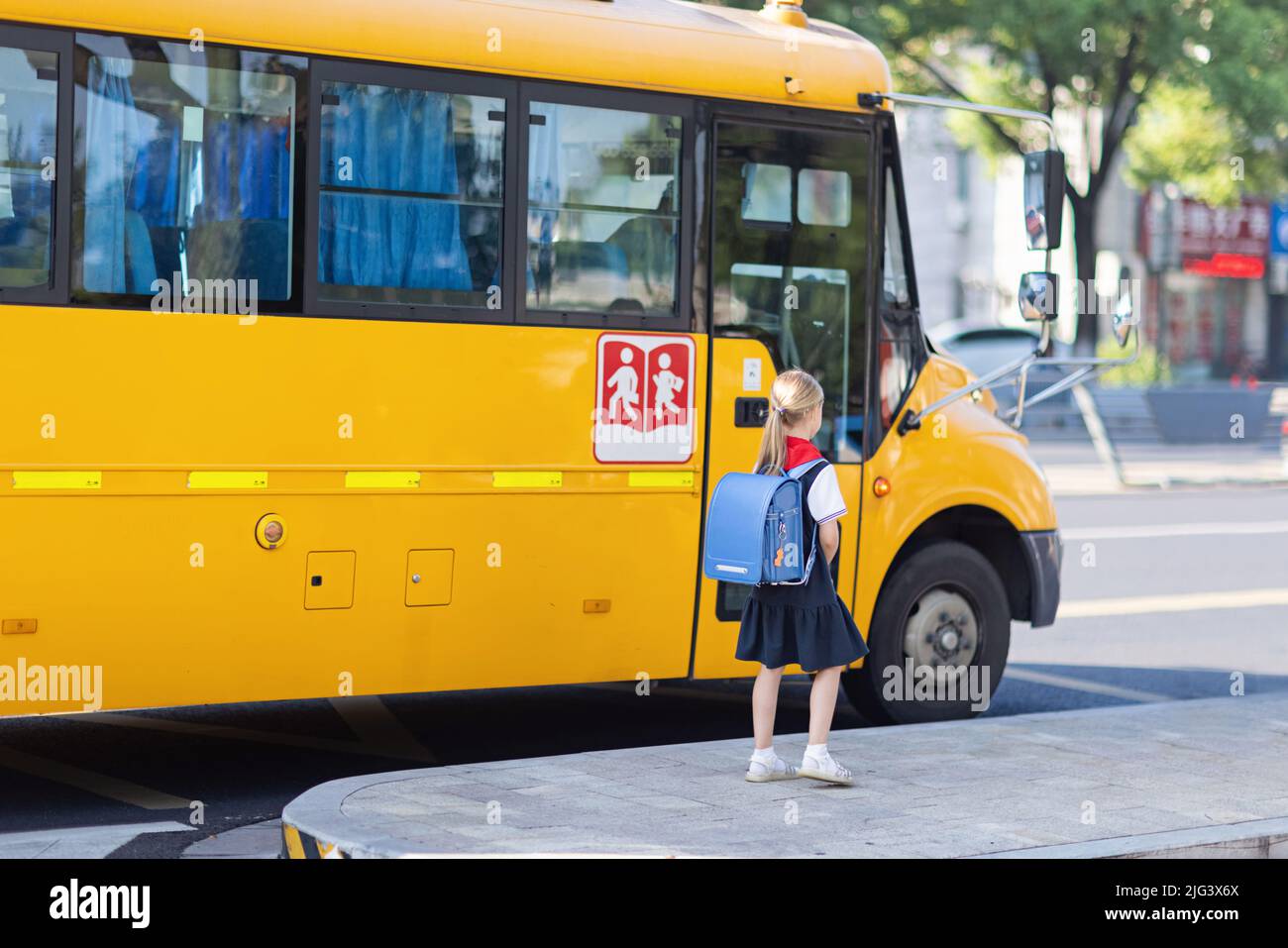Back to school. Little girl from elementary school outdoor near yellow ...