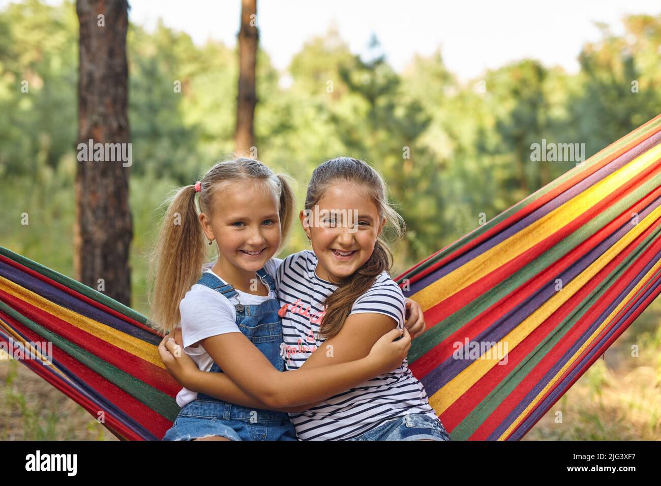 Kid girls relax in colorful rainbow hammock Stock Photo - Alamy