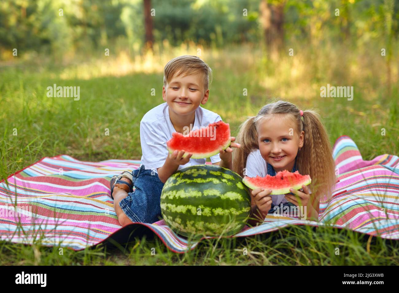 Cute kids eating watermelon in the garden Stock Photo - Alamy