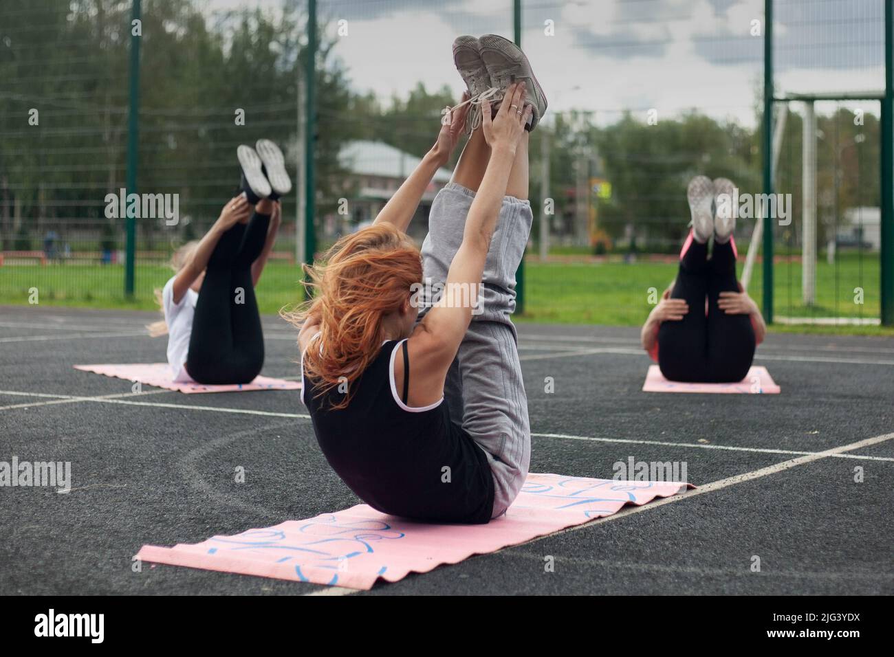 Fitness classes on the street. A woman exercises her muscles. The girl ...