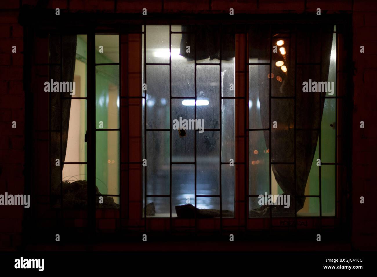 Window is in dark. Window light in city. Grille on building at night ...