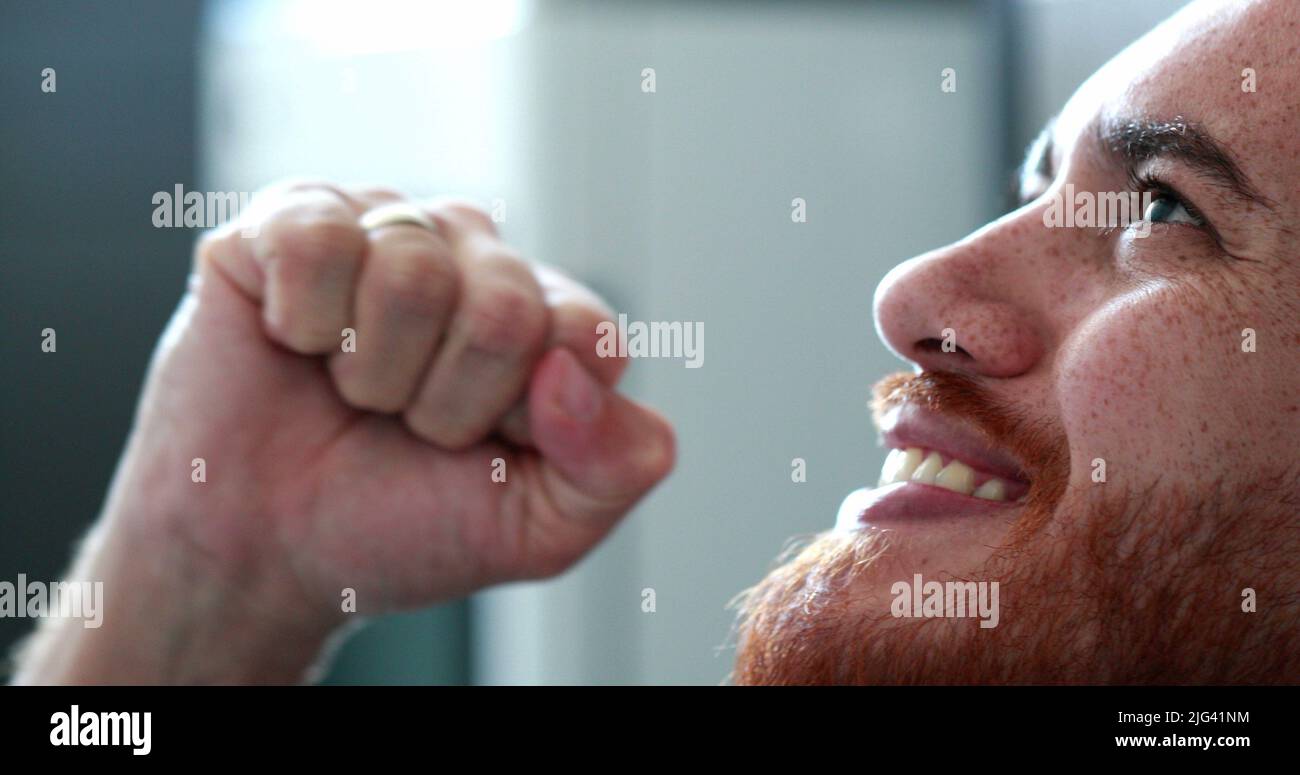 Victorious man celebrating with fist in air looking up to sky with hope ...