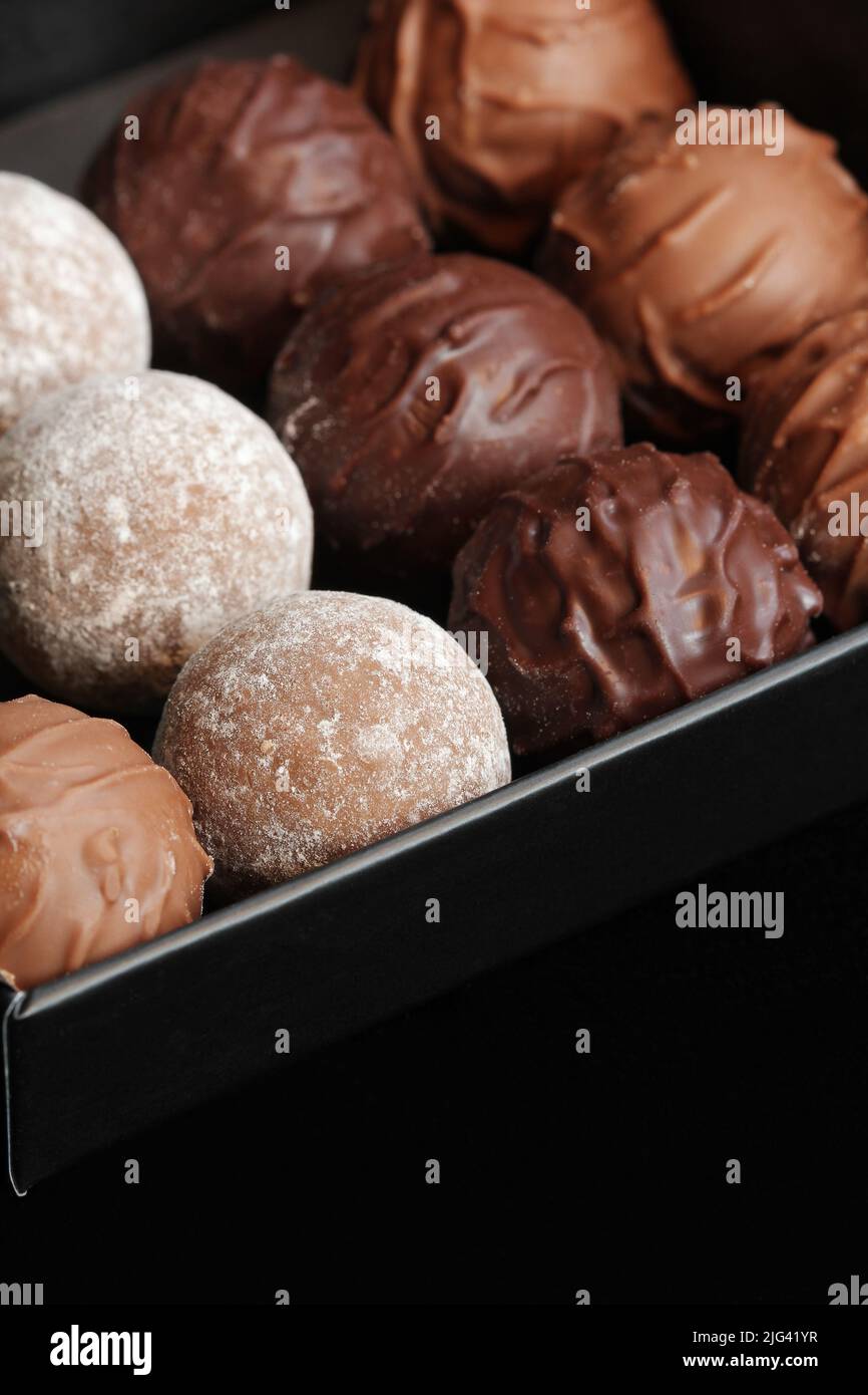 Swiss chocolates assorted in a gift box, on black background with empty ...
