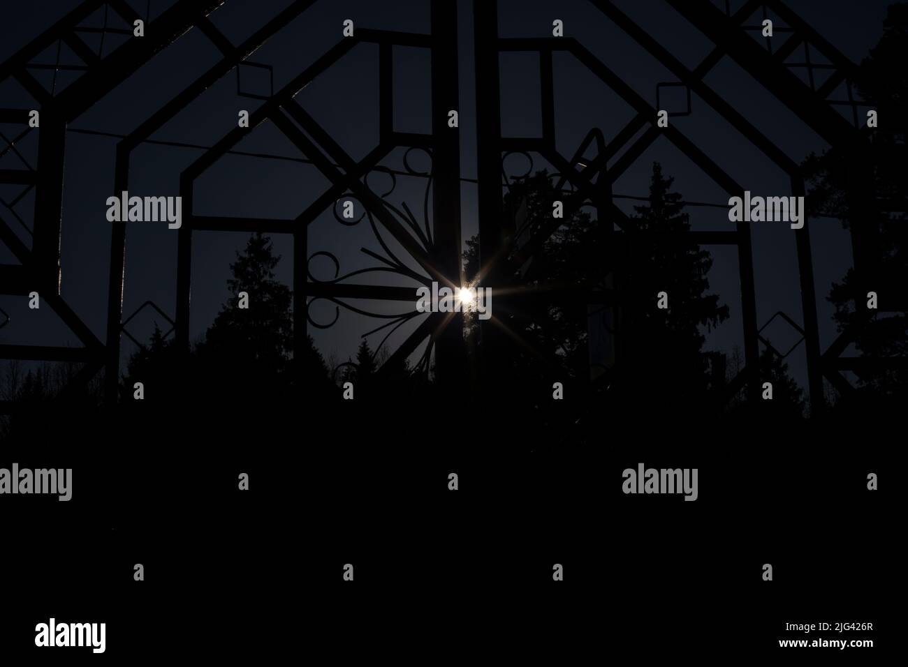 Sun shines through fence. Dark fence. Light on metal Stock Photo - Alamy