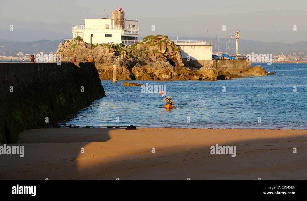 A male canoeist paddling near the beach next to the Sailing school of ...