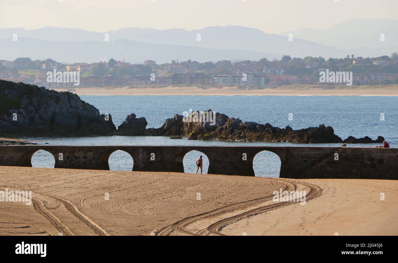 Landscape view with a man framed by arches of a stone jetty on the ...