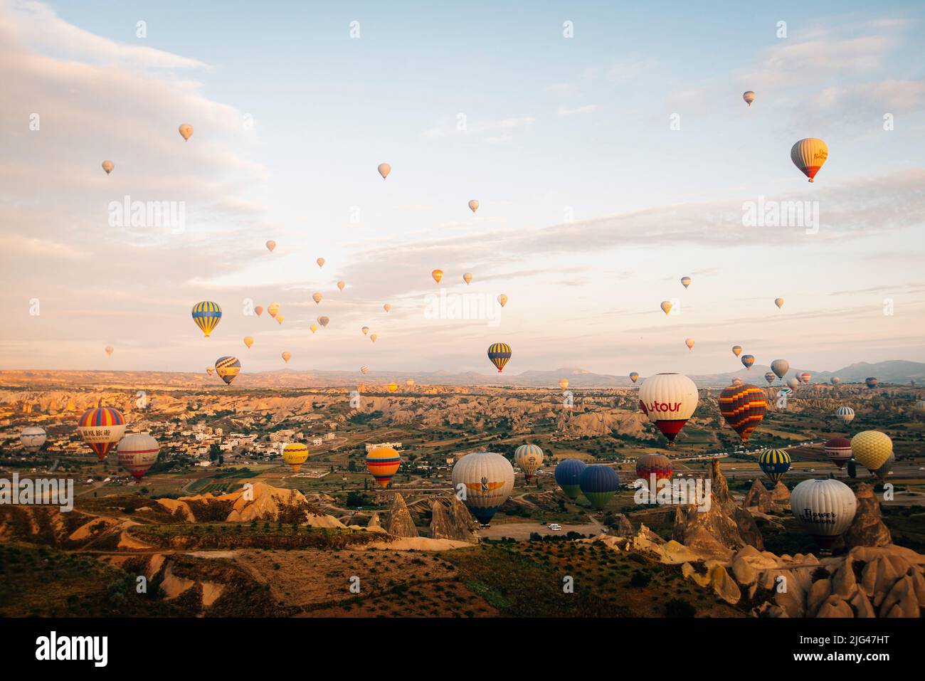 Hot air balloons flying over fairy chimneys at sunrise in Cappadocia ...