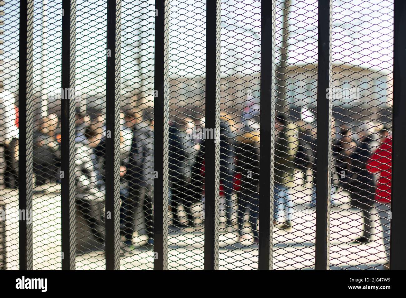 Fence behind which people. Black fence in public place. People are in ...