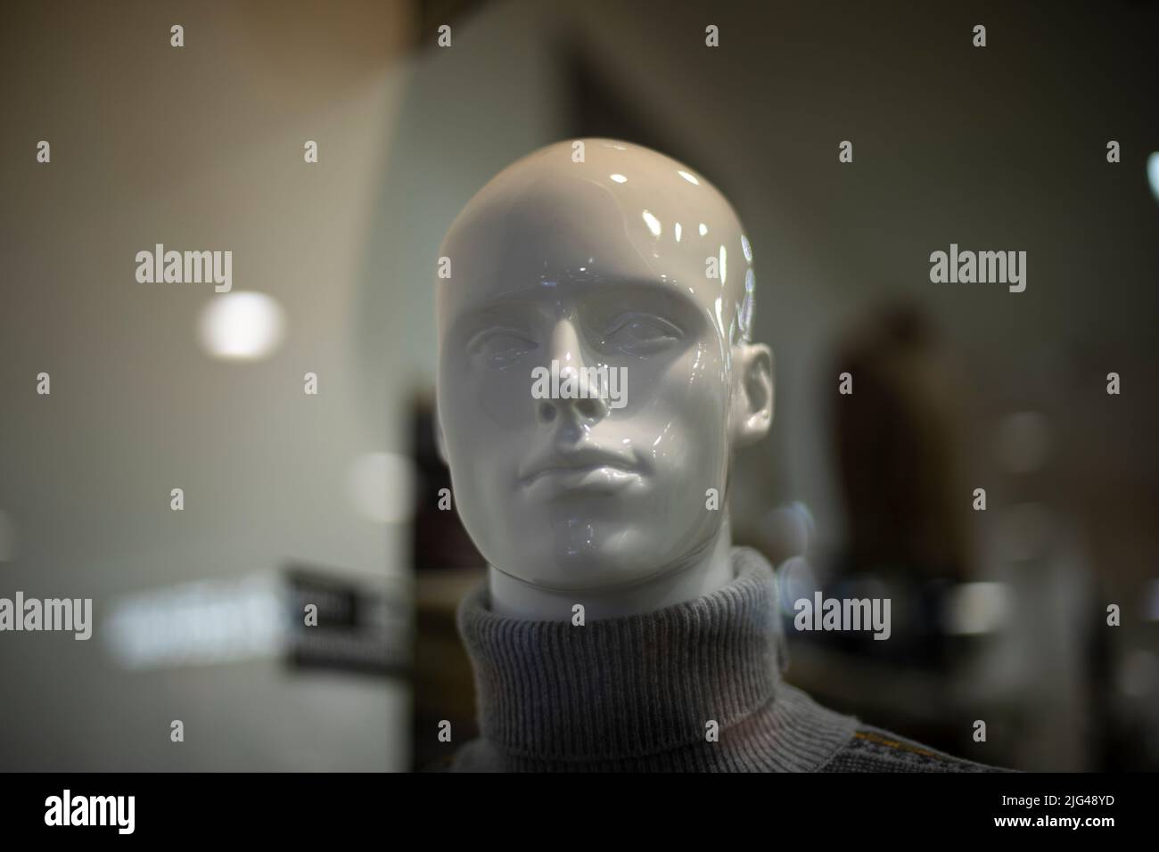 Mannequin in clothing store. Head is made of white plastic. Light on ...