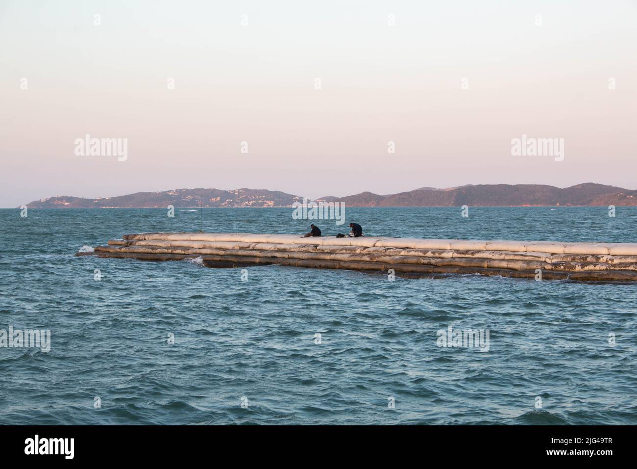 Turtle channel at sunset with two people fishing in Buzios, Brazil ...