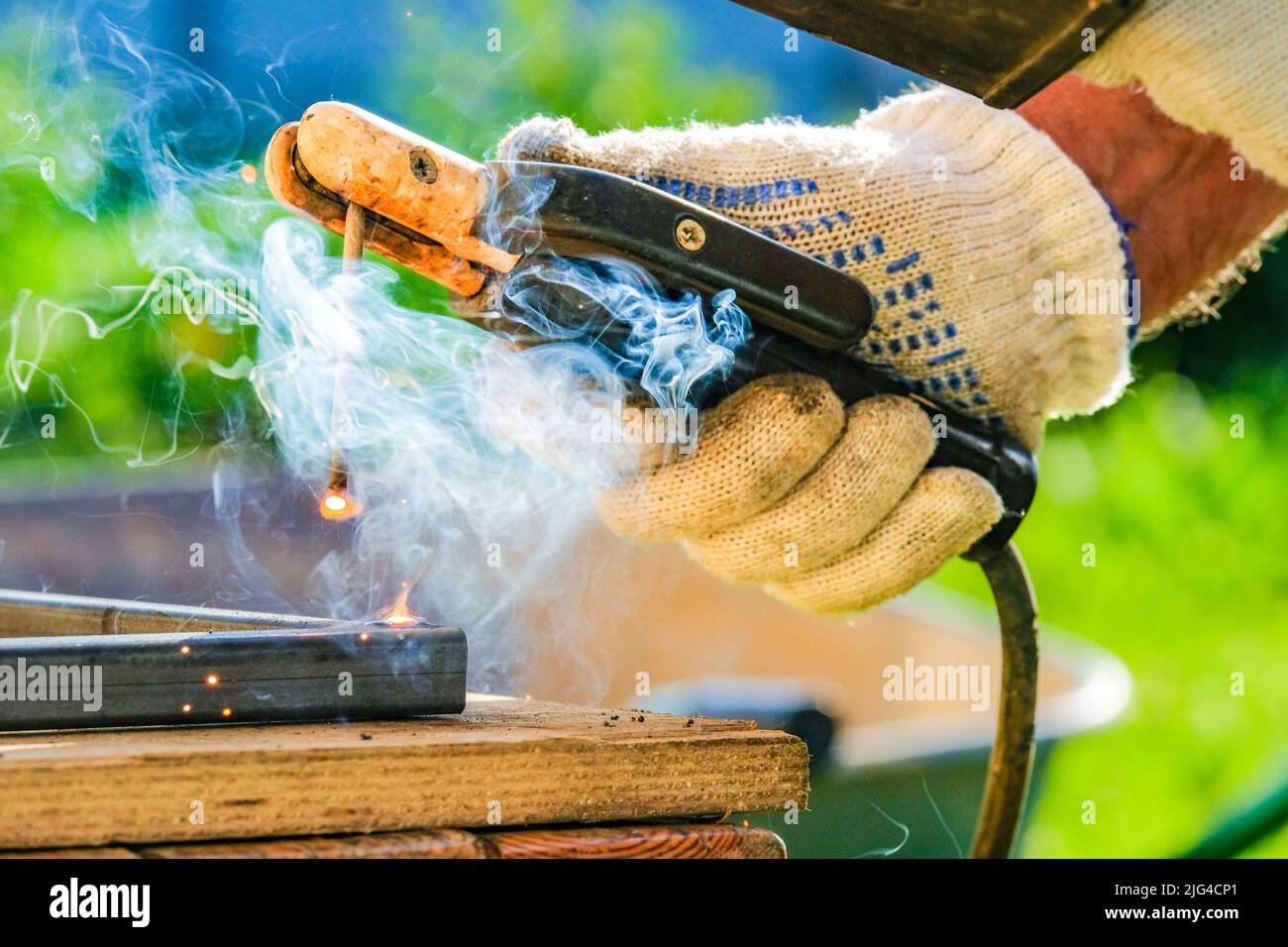 Selective focus on a hot electrode in the hand of a welder welding ...