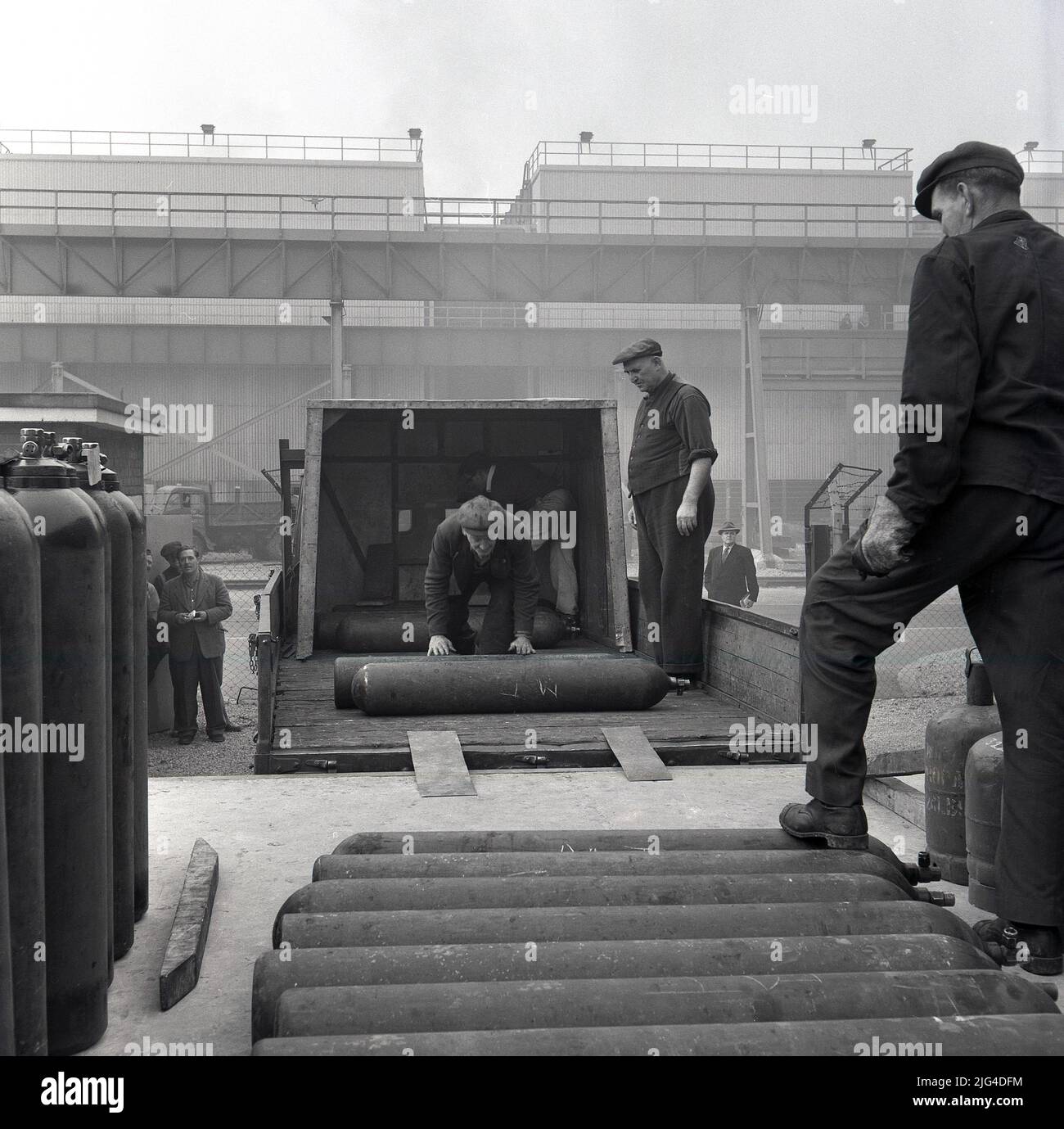 1950s, historical, steel cyclinders or cannisters being loaded at the ...