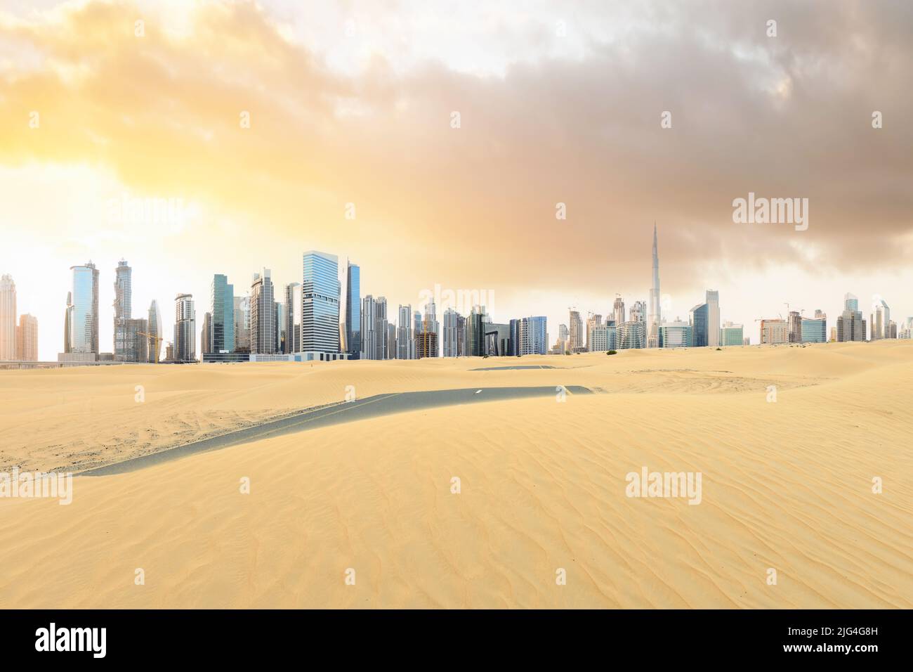 Stunning view of a road covered by sand dunes with the Dubai Skyline in ...
