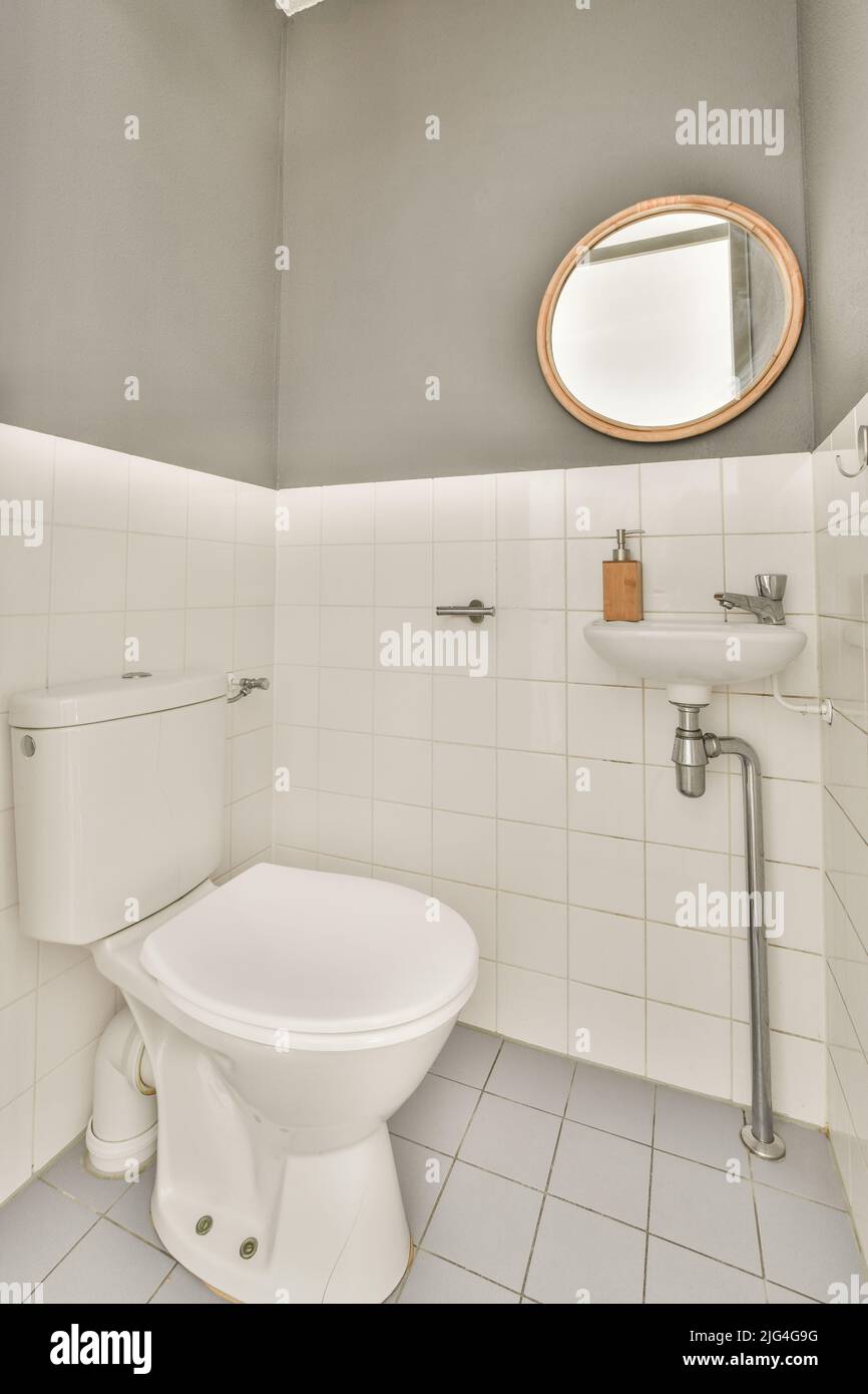 Modern Flush Toilet And Ceramic Sink Installed On White Tiled Walls