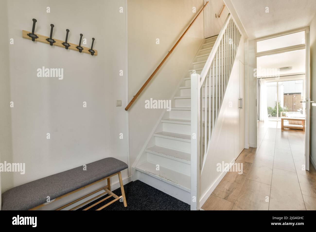 White hallway with wooden stairway leading to second floor of modern ...