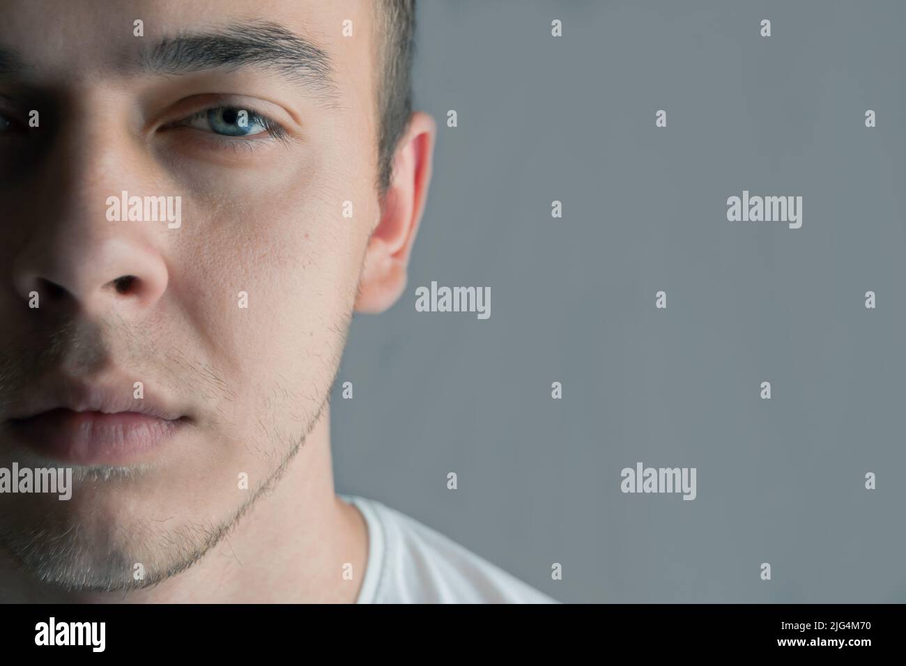 Portrait of a beautiful young man with blue eyes, half face, space for ...