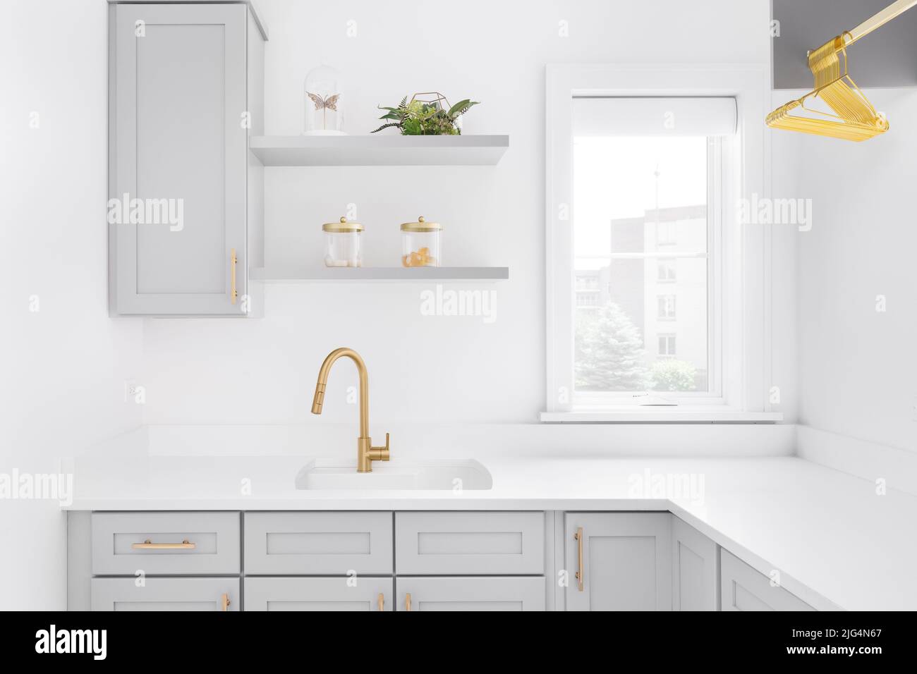 A laundry room detail shot with a gold faucet and hardware, grey ...
