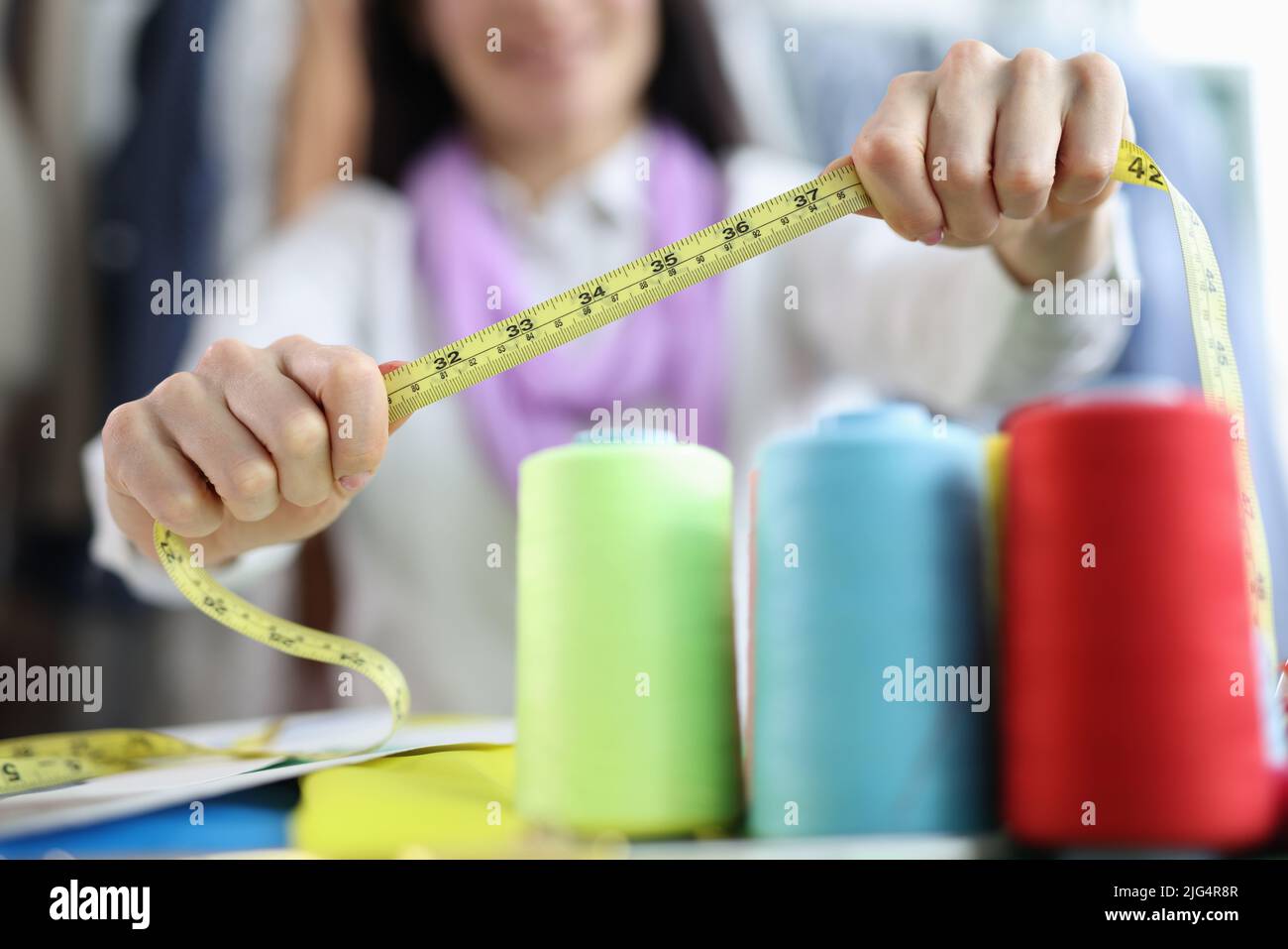 Seamstress holds tape measure in sewing workshop Stock Photo - Alamy