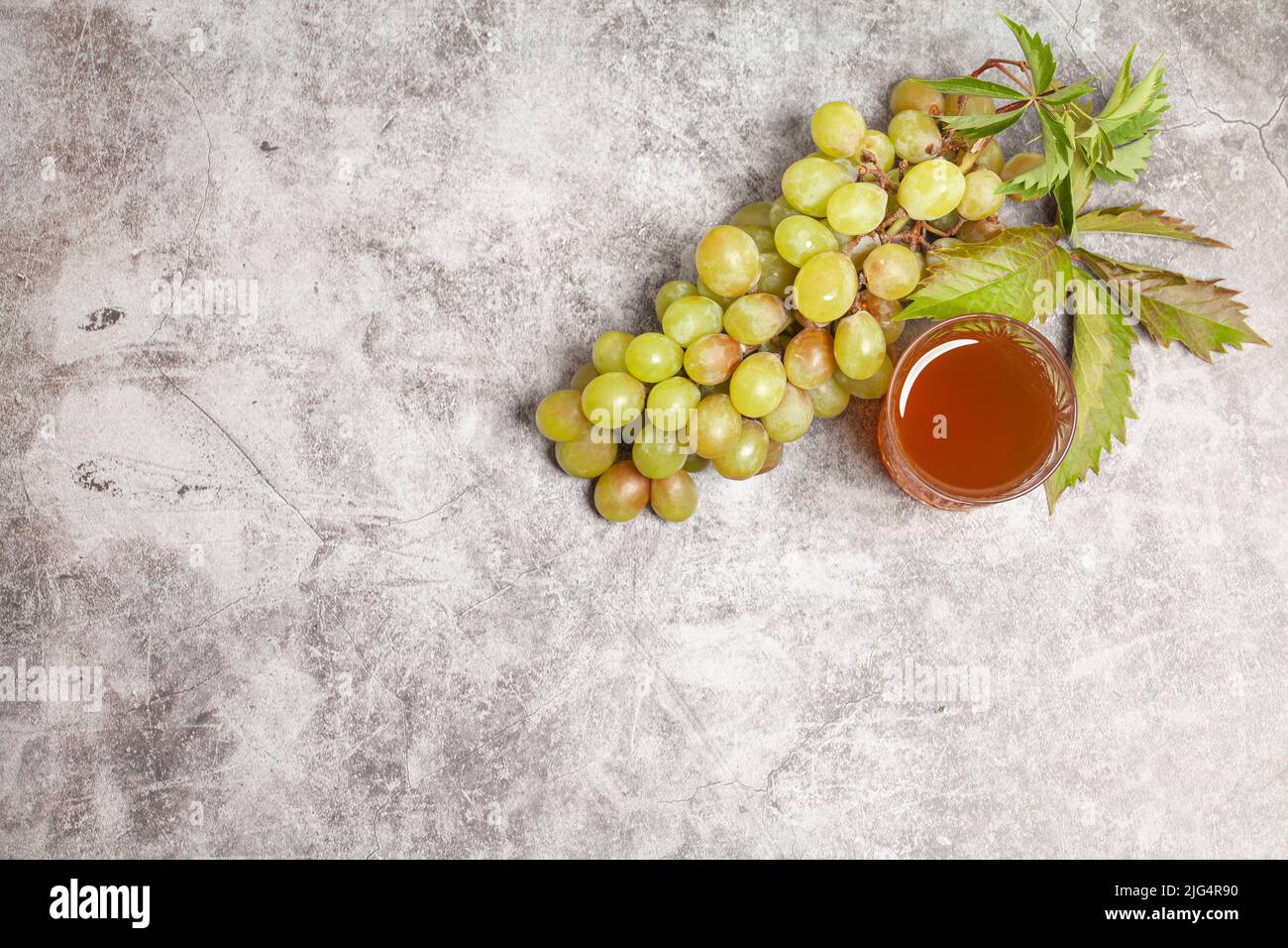 Glass of White Wine or Grape Juice and Branch of Green Grapes on Gray ...