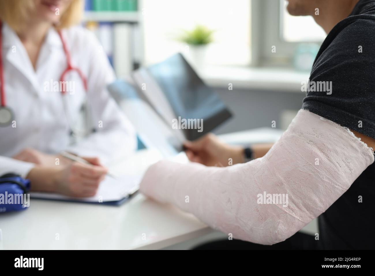 Doctor conducts medical consultation with patient with cast on arm ...