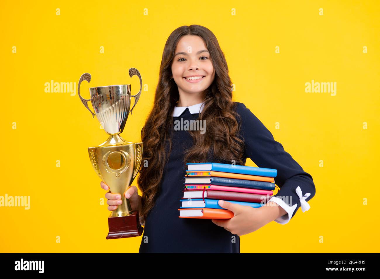 Schoolgirl in school uniform celebrating victory with trophy. Teen ...
