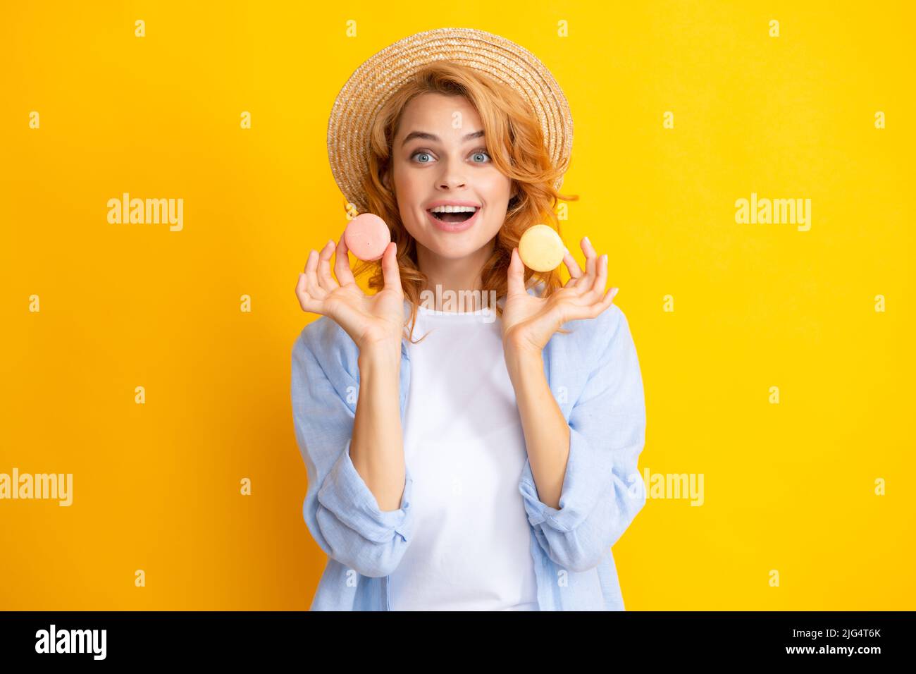 Young pleased woman isolated over yellow background eating macaroons ...