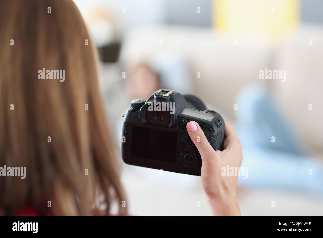 Woman holds professional black camera in hands and photographs model at ...