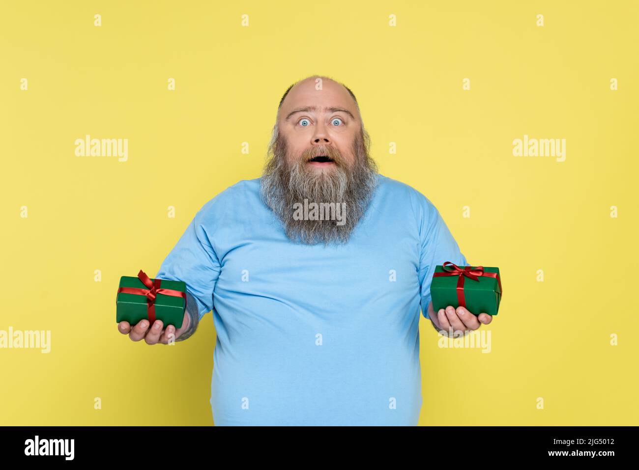 amazed plus size man with open mouth and bulging eyes holding presents ...