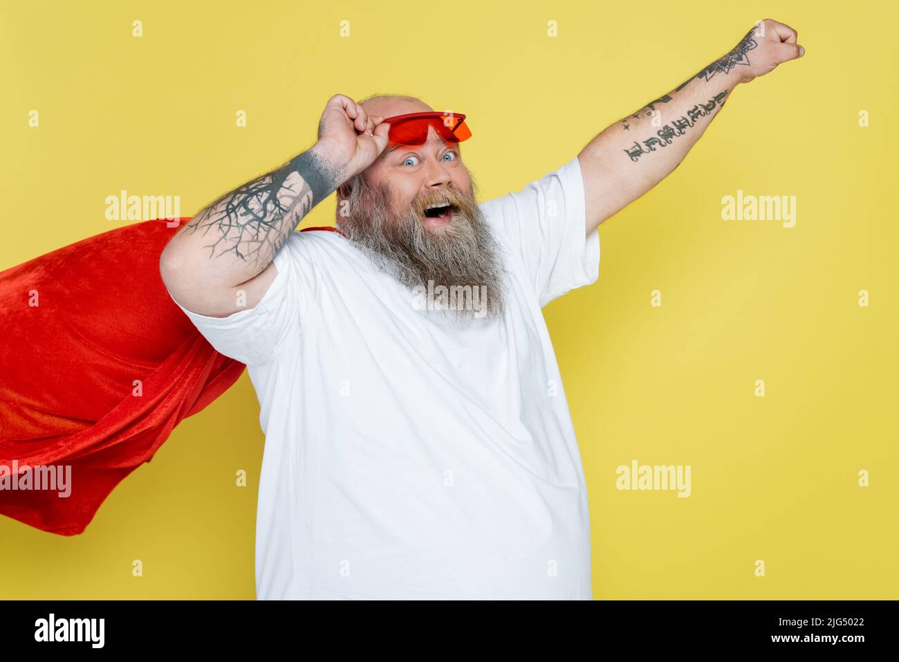 tattooed plus size man in superhero cloak posing with outstretched hand ...