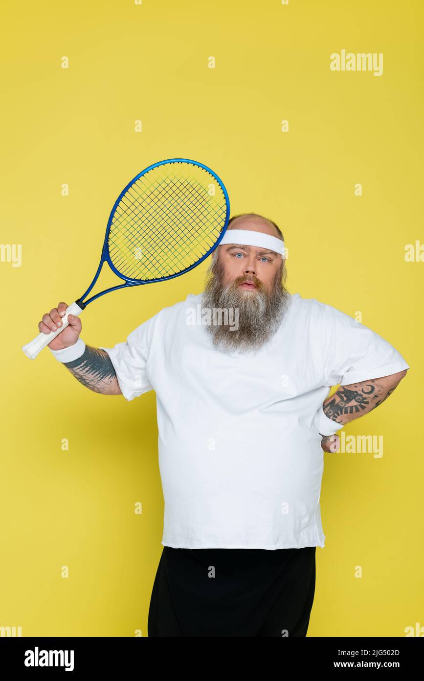 bearded plus size tennis player standing with hand on waist and looking ...