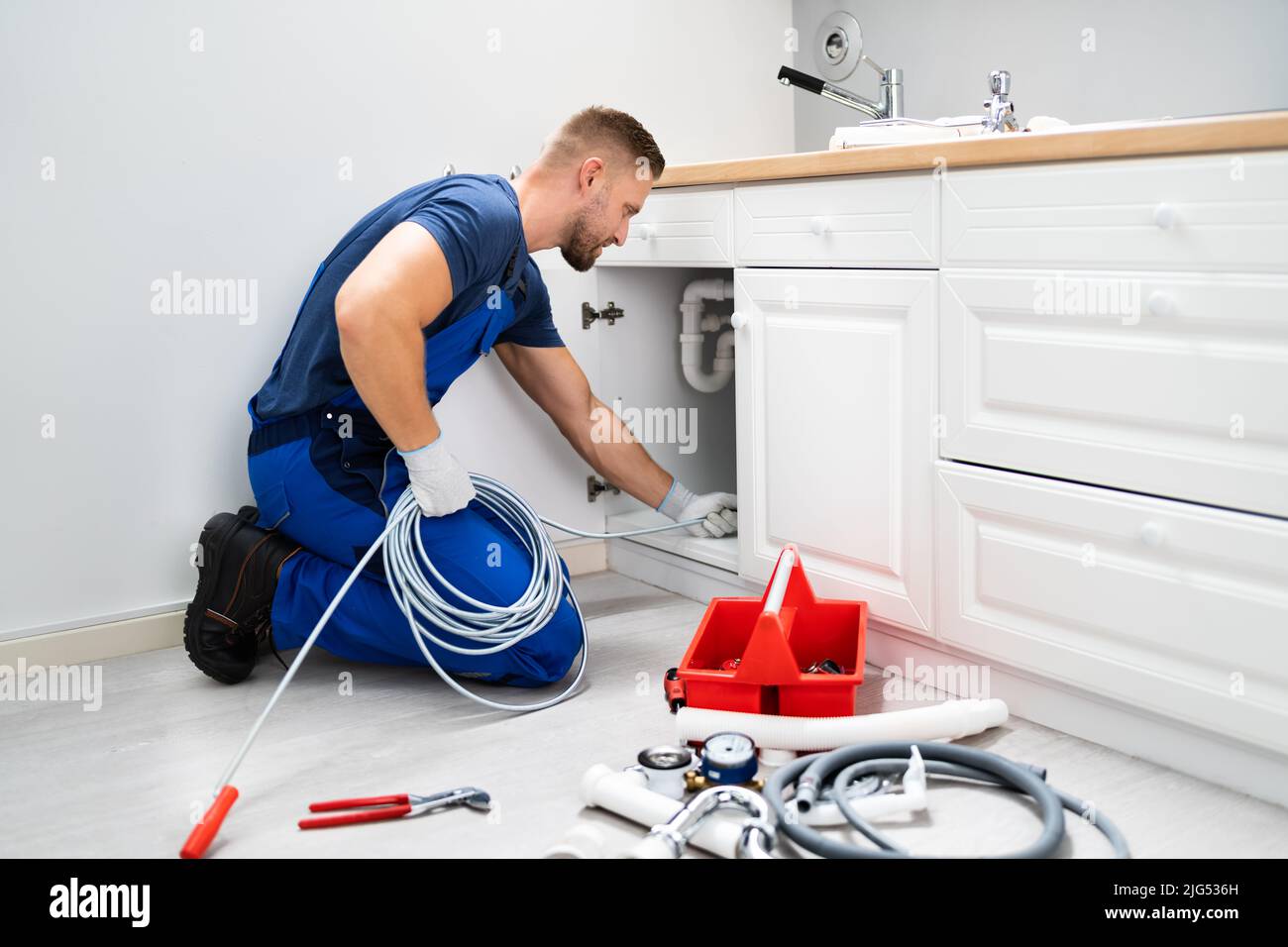 Male Plumber Cleaning Clogged Sink Pipe In Kitchen Stock Photo - Alamy