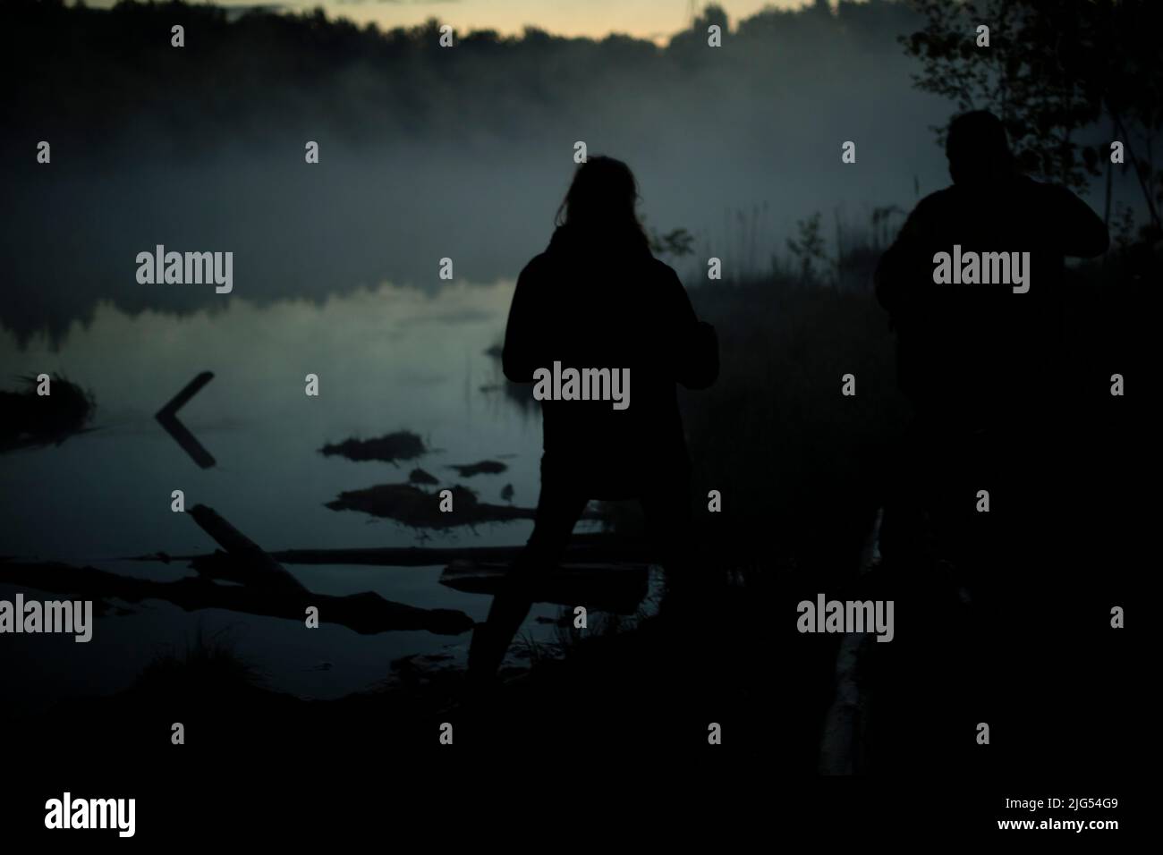 Man in fog before dawn. Rest on lake. Silhouette of man at night in ...