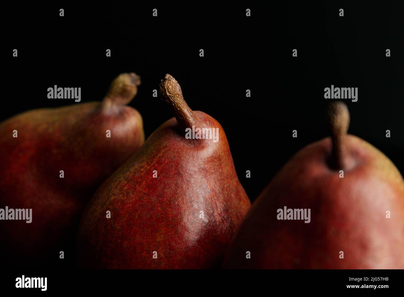 three red pears on a black table Stock Photo - Alamy