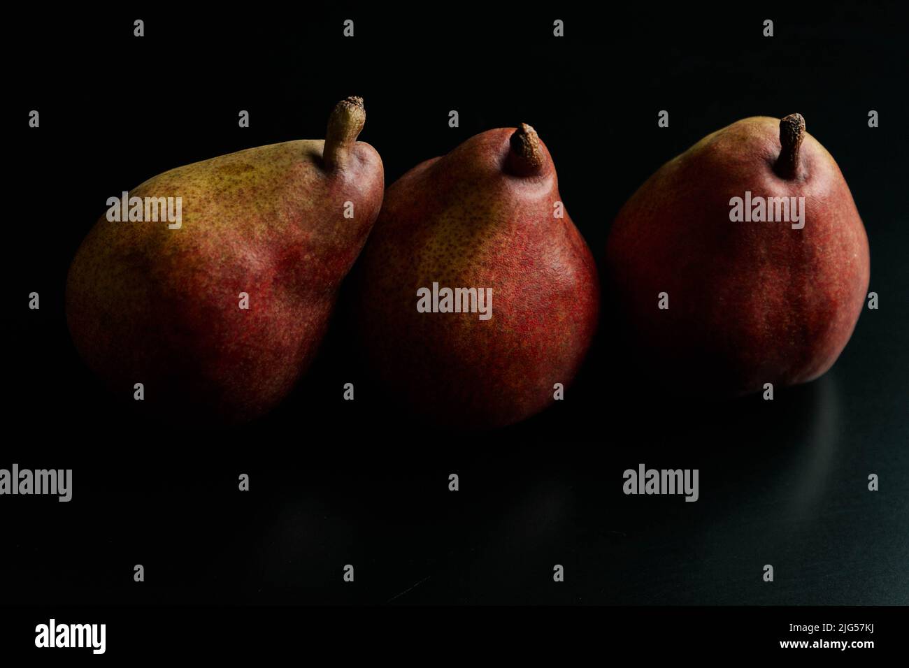 three red pears on a black table Stock Photo - Alamy