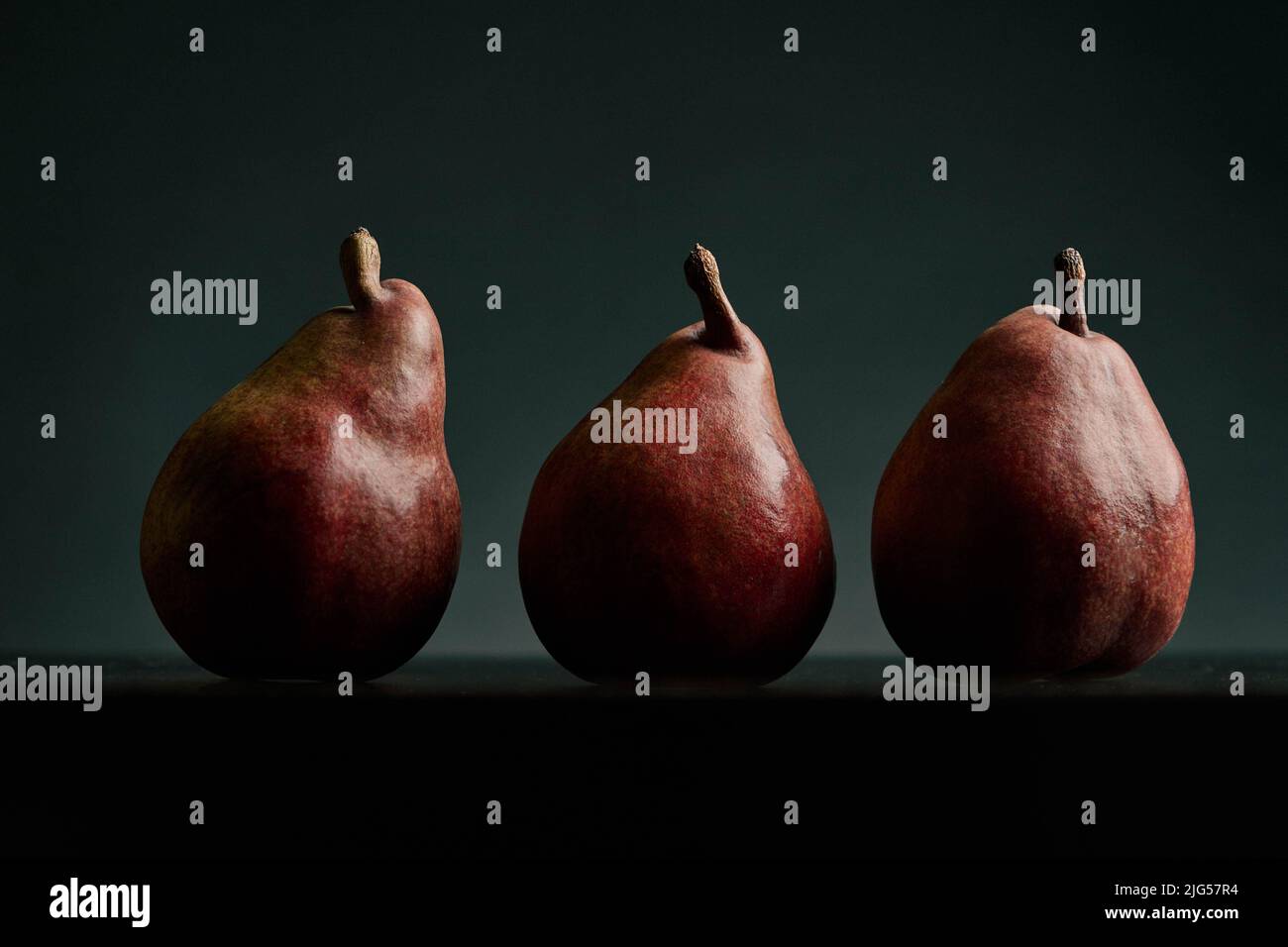 three red pears on a black table Stock Photo - Alamy
