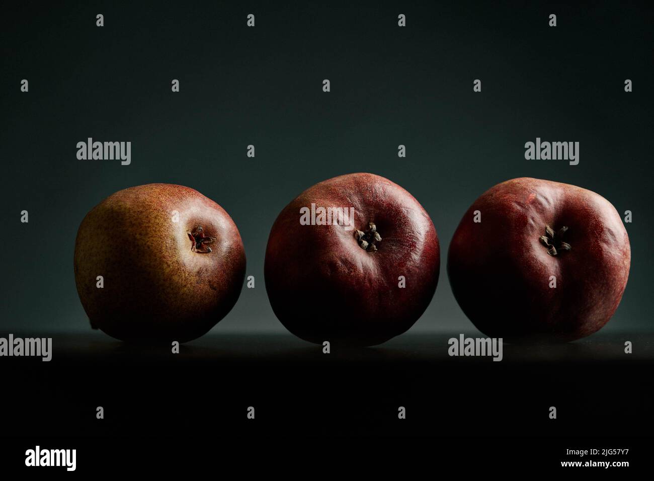three red pears on a black table Stock Photo - Alamy