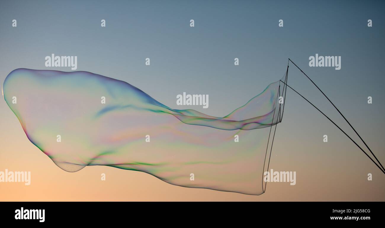Giant colorful bubble. Big soap bubble on blue sky. Huge soap bubbles ...