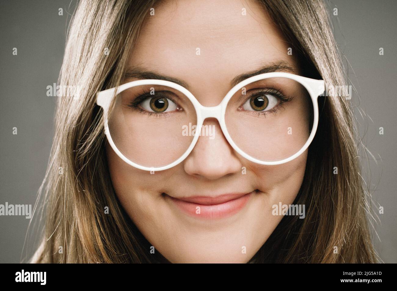 Being smart is in. Shot of a young woman wearing retro glasses against ...