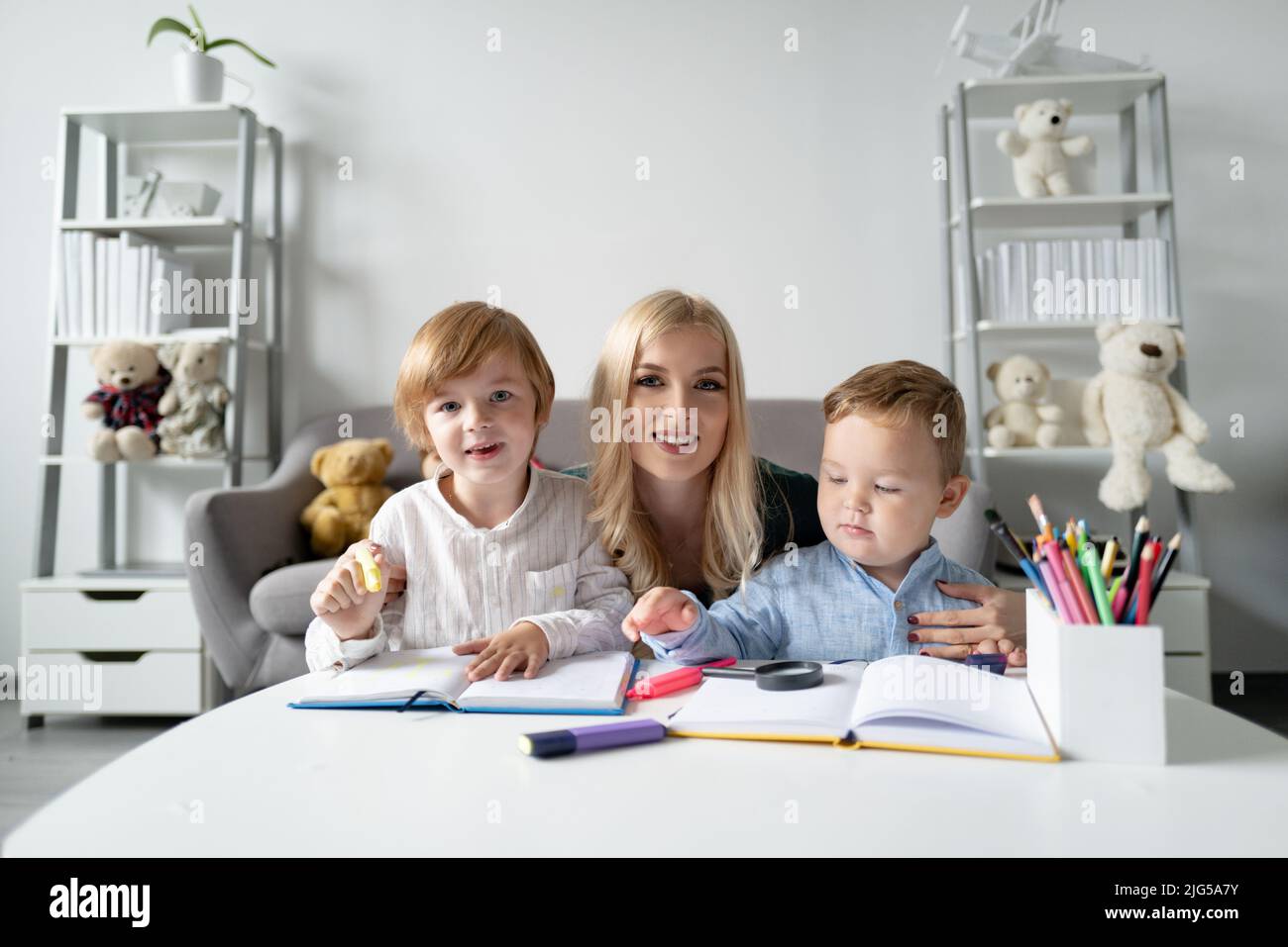 Children drawing in kindergarten. Teacher mom working with creative ...