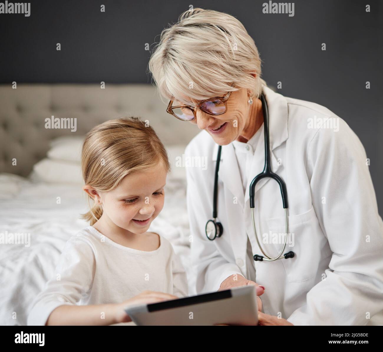 How are you feeling today. Shot of a girl and a doctor using a tablet ...