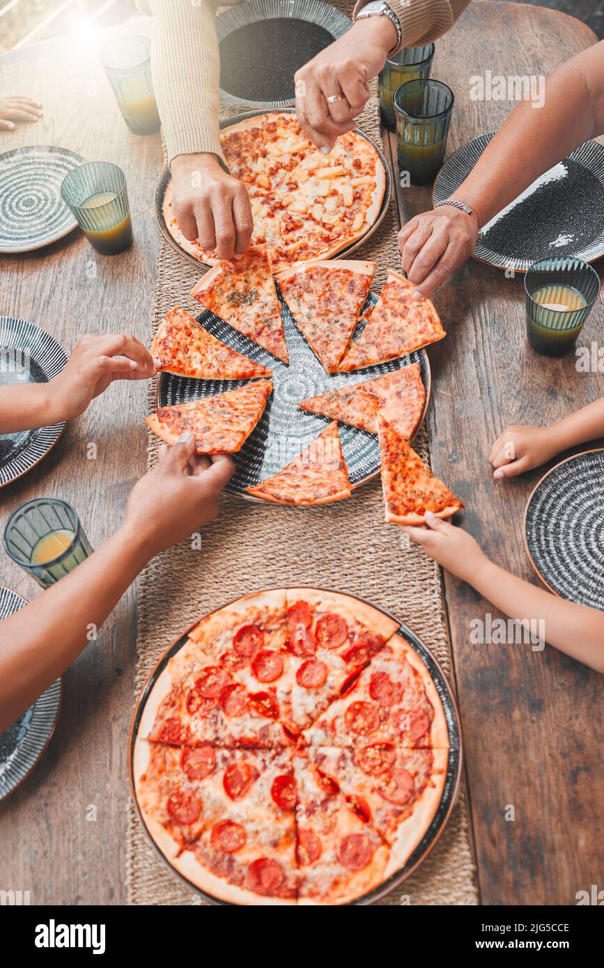 Up for grabs. Shot of an unrecognizable family sharing pizza outside ...