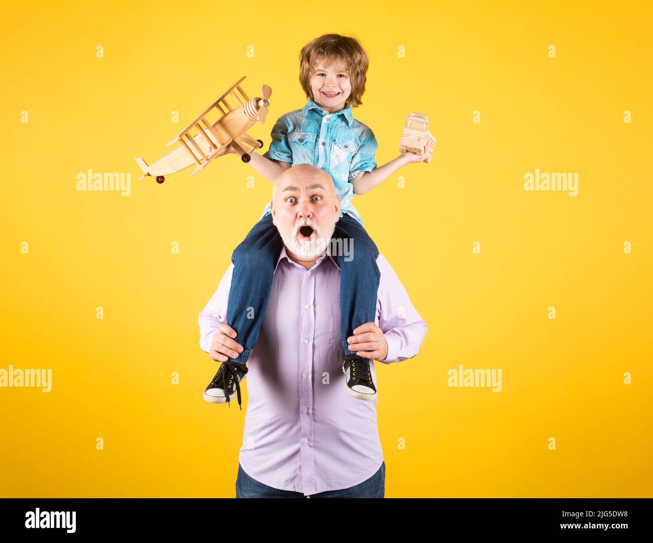 Grandson child and grandfather piggyback ride with plane and wooden toy ...