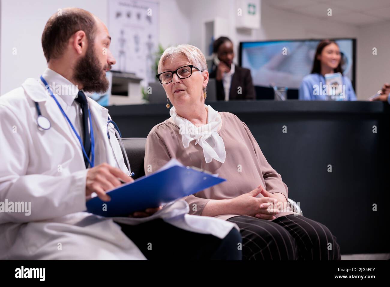 General practitioner consulting senior woman at reception lobby in ...