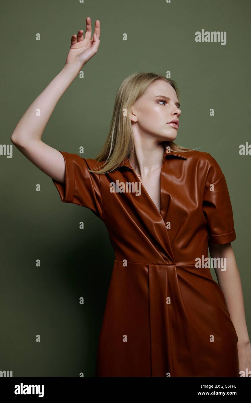 Dancing elegant pretty young blonde female in leather brown dress ...