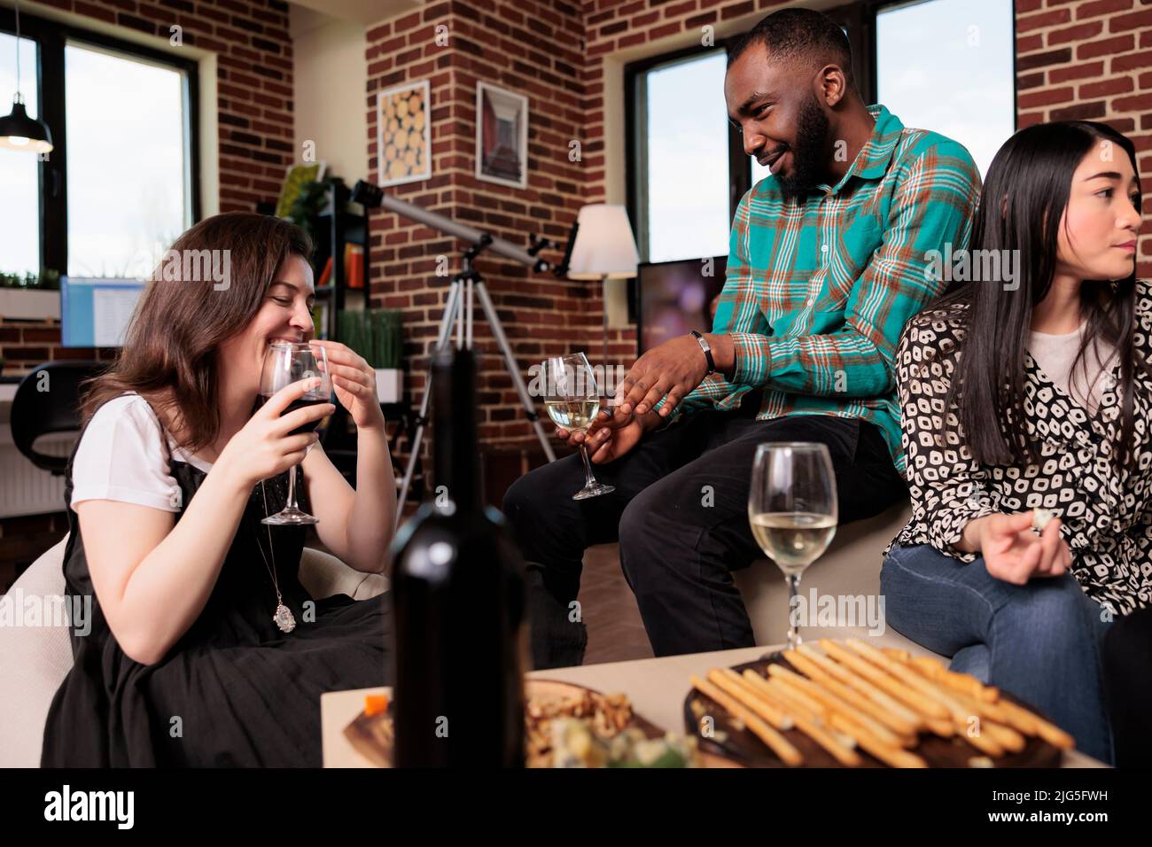 Close diverse friends having fun at wine party while bonding in living ...
