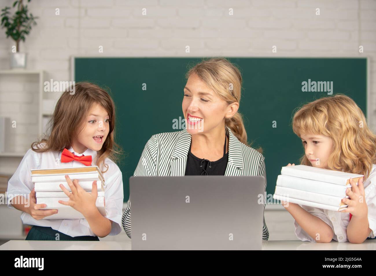 School teacher with a schoolkids learning at laptop computer, studying ...