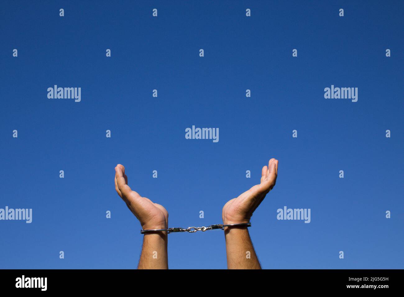 Image of a man's hands facing the sky with handcuffs on his wrists ...