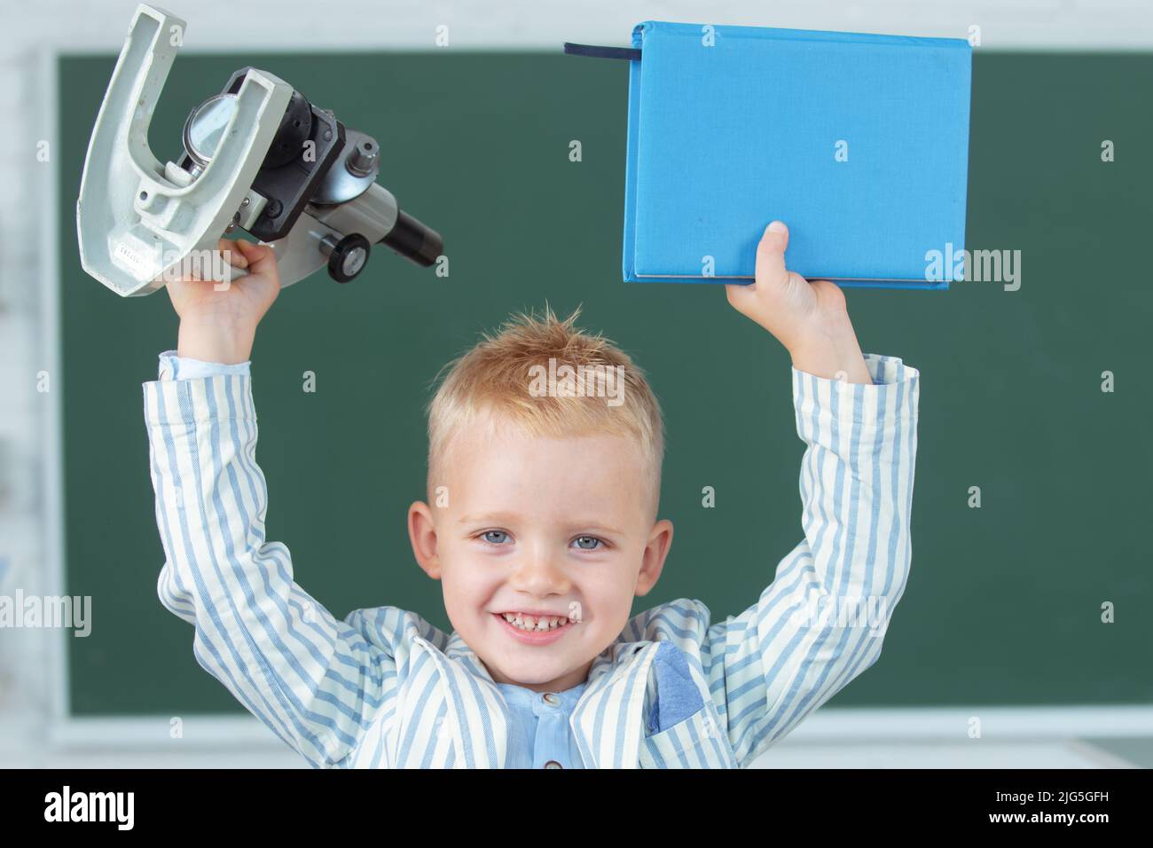 Amazed school boy with microscope and book. School child student learn ...