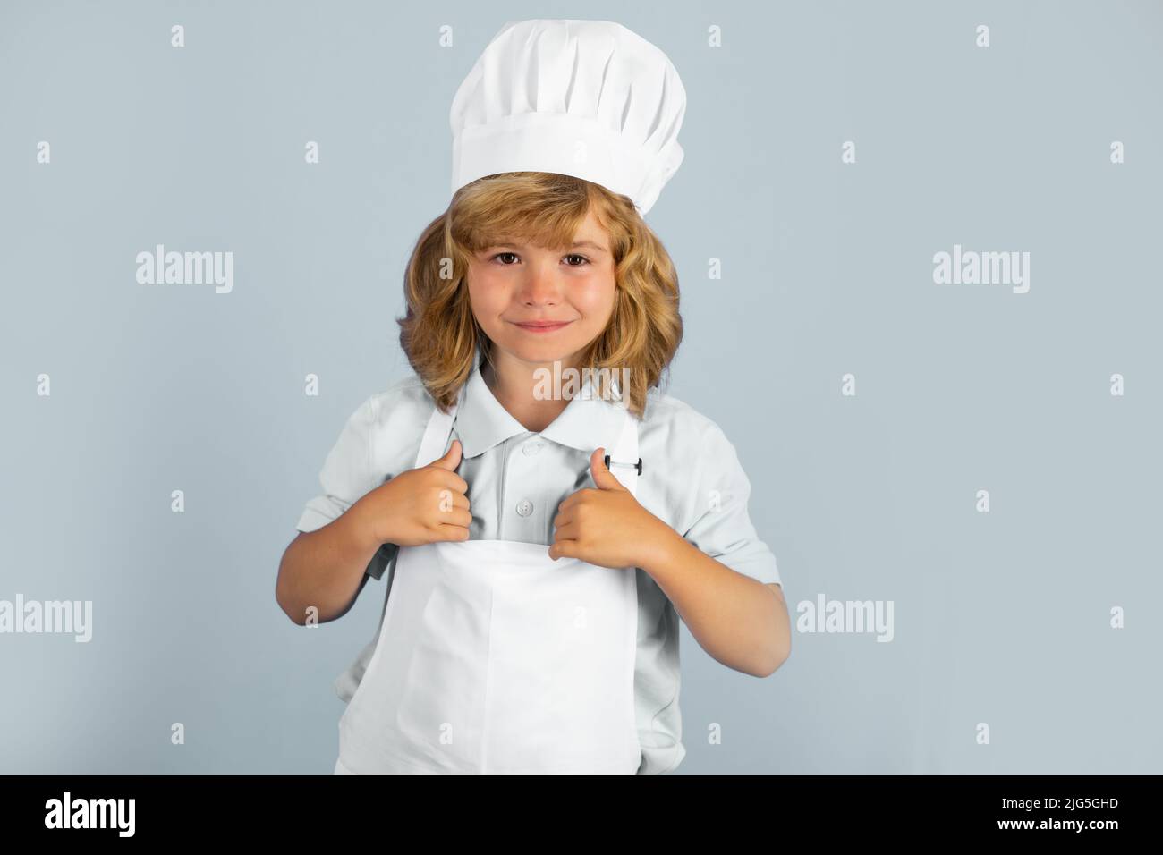 Kid boy in chef hat and apron cooking preparing meal. Chef funny face ...