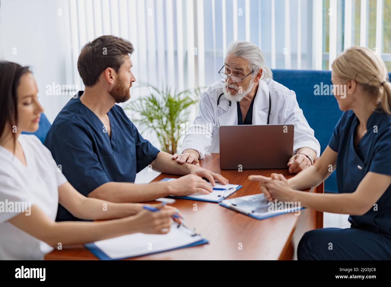 Group of doctors sitting at meeting table in conference room during ...